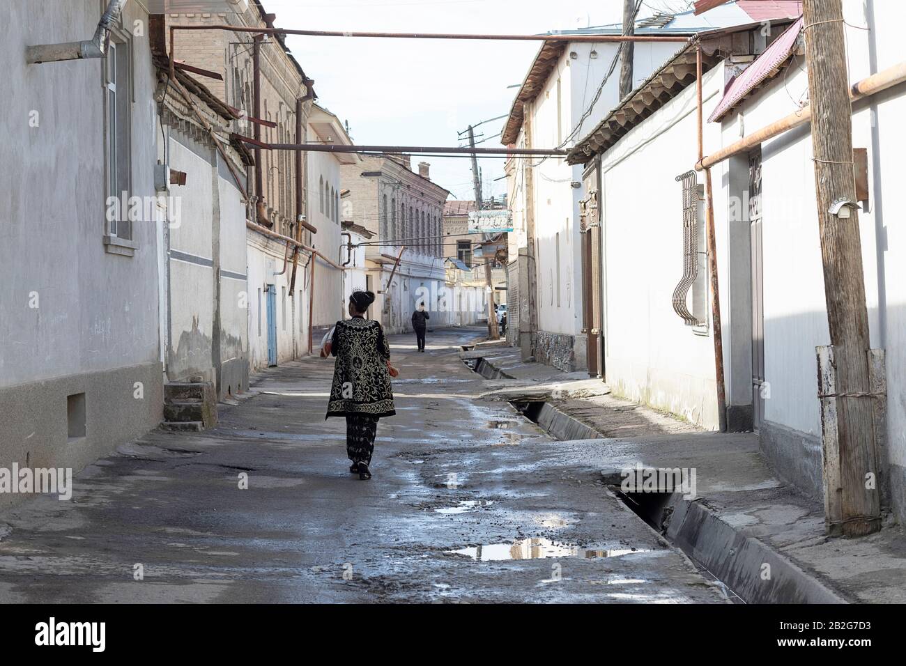 Woman in traditional outfit walking on back street of old town of ...
