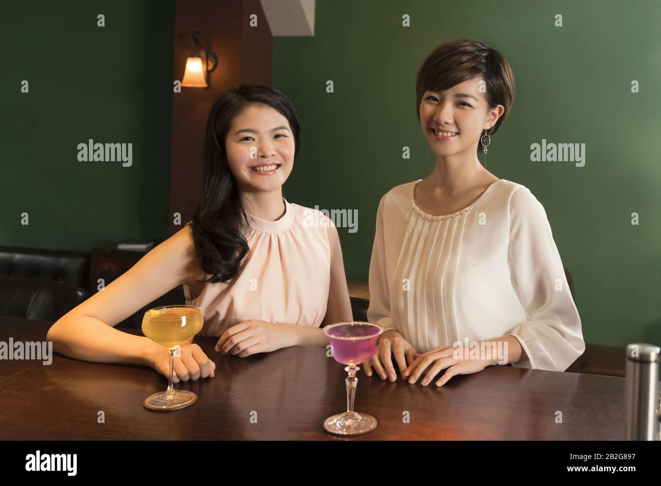 Two young women enjoying cocktails at bar Stock Photo - Alamy