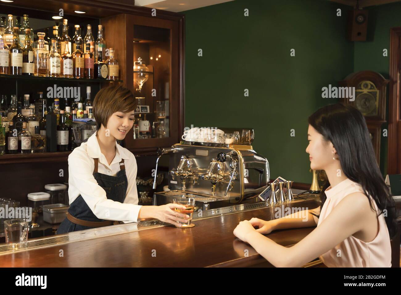 Female bartender serving drink to woman Stock Photo - Alamy