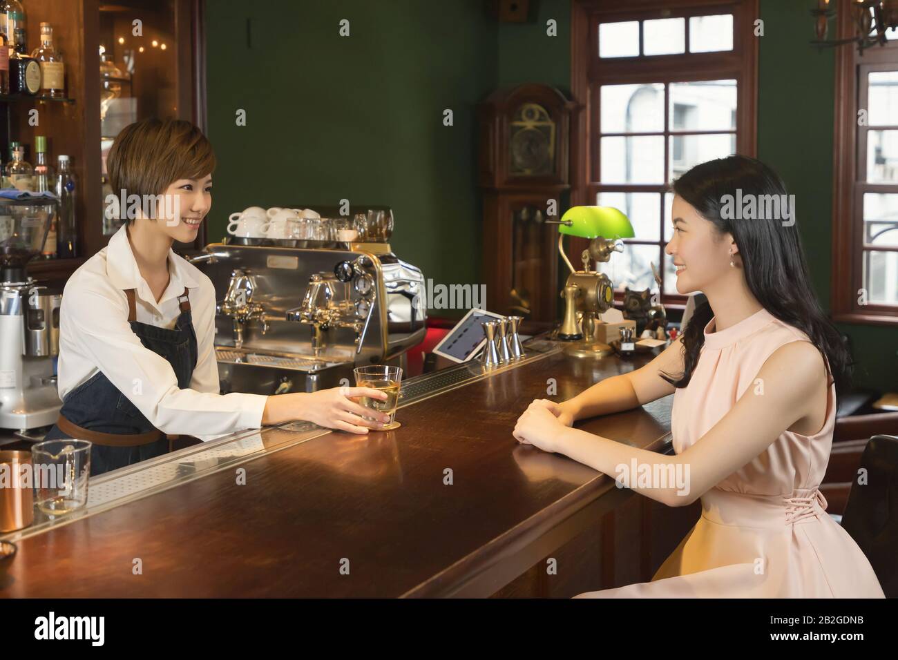 Female bartender serving drink to woman Stock Photo - Alamy