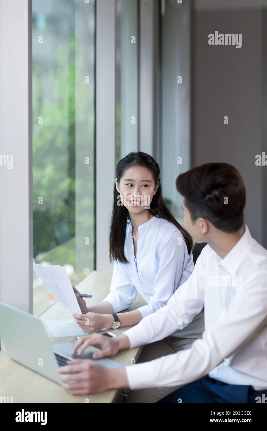Two smiling young businesspeople talking while working in office Stock ...