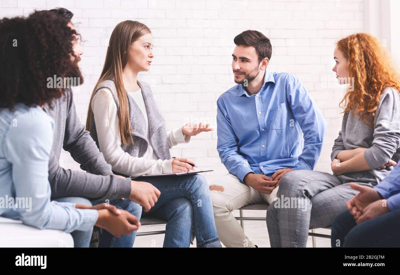 People sitting in circle and listening mentor during group therapy ...
