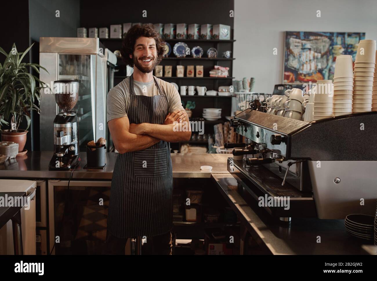 Successful male business owner behind the counter of a coffee shop with ...