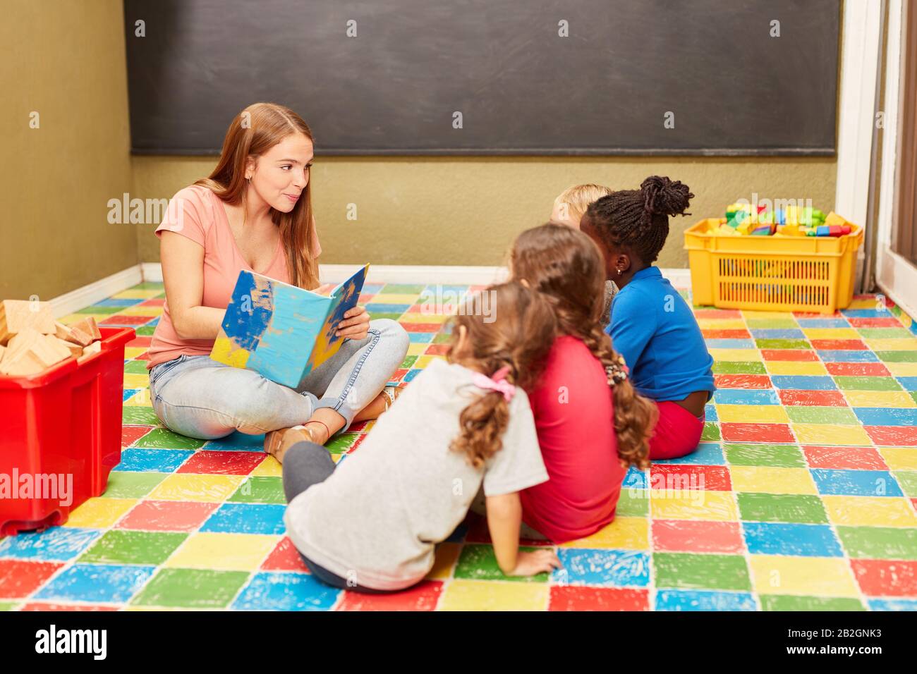 Group of children and educator reading a children's book in ...