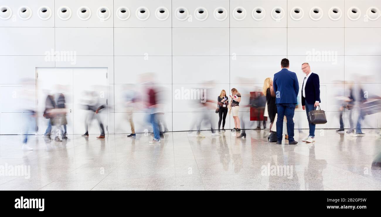 Group of business people is standing in anonymous blurred crowd at a ...