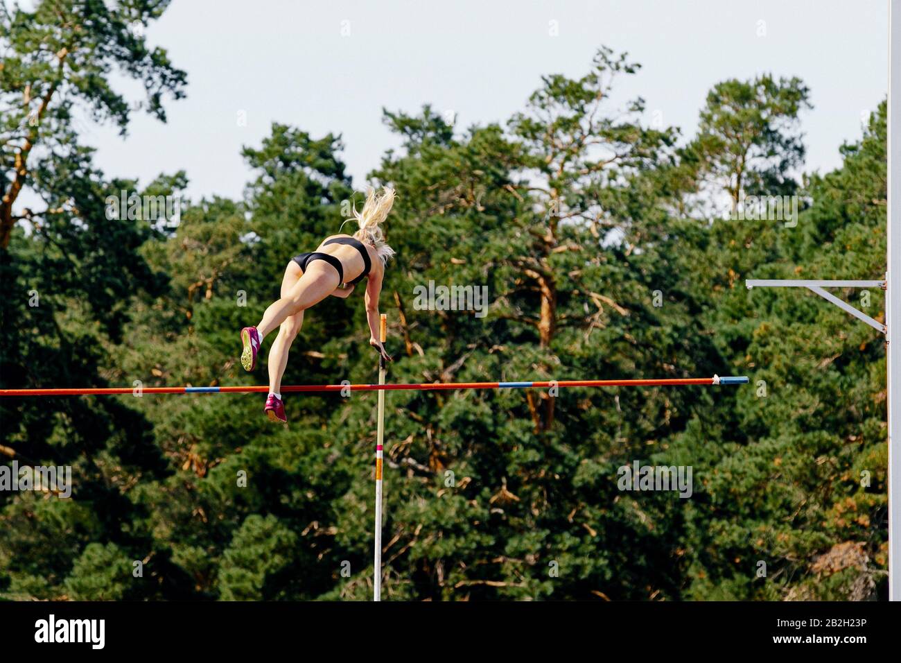 pole vault woman athlete jump on background of forest Stock Photo - Alamy