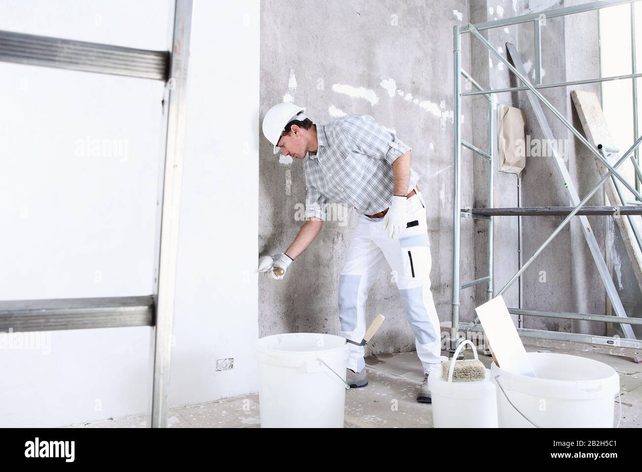 plasterer man at work with trowel plastering the wall of interior ...