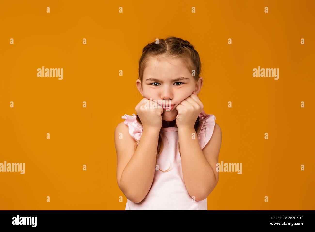 offended sad little child girl in dress on yellow background. Human ...