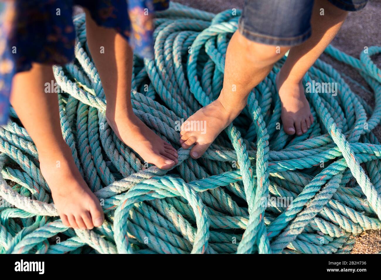 The feet of two children on fishing ropes Stock Photo - Alamy