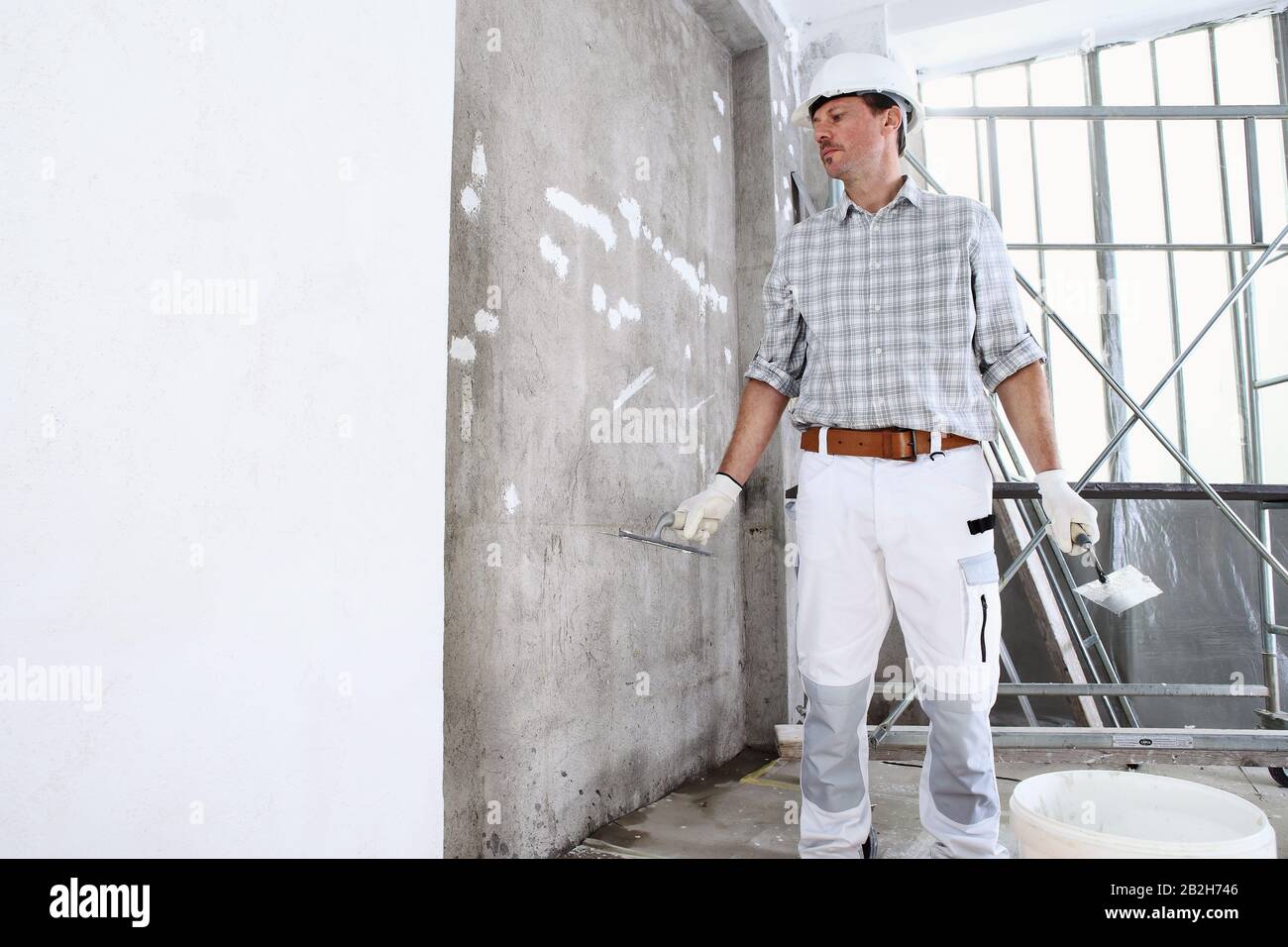 plasterer man at work with trowel plastering the wall of interior ...