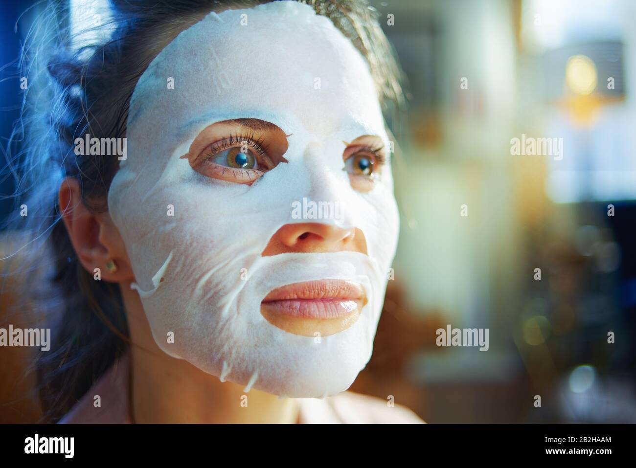 Portrait of elegant 40 years old housewife in pajamas with white sheet ...