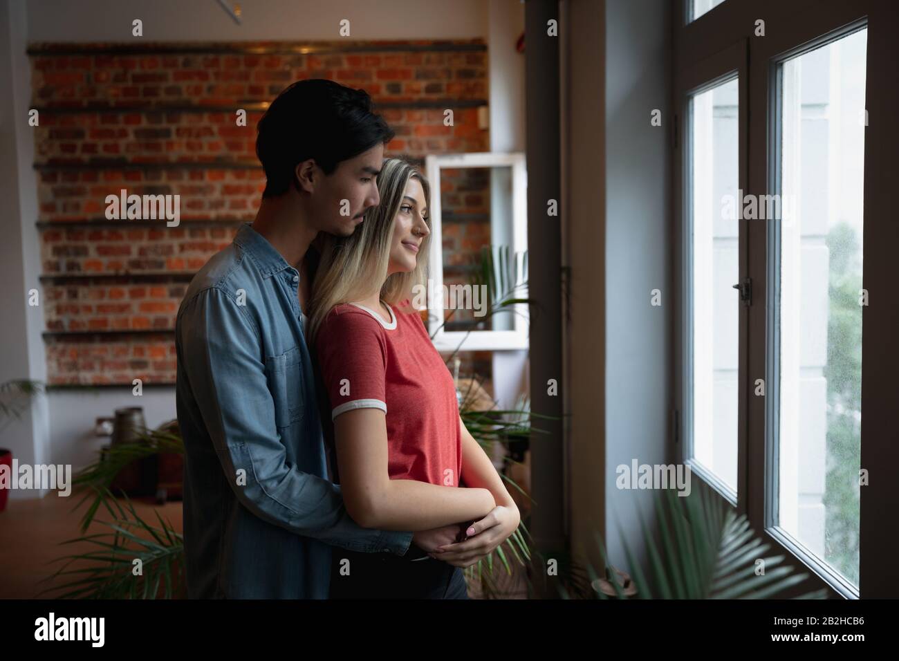 Young couple looking through the window Stock Photo - Alamy