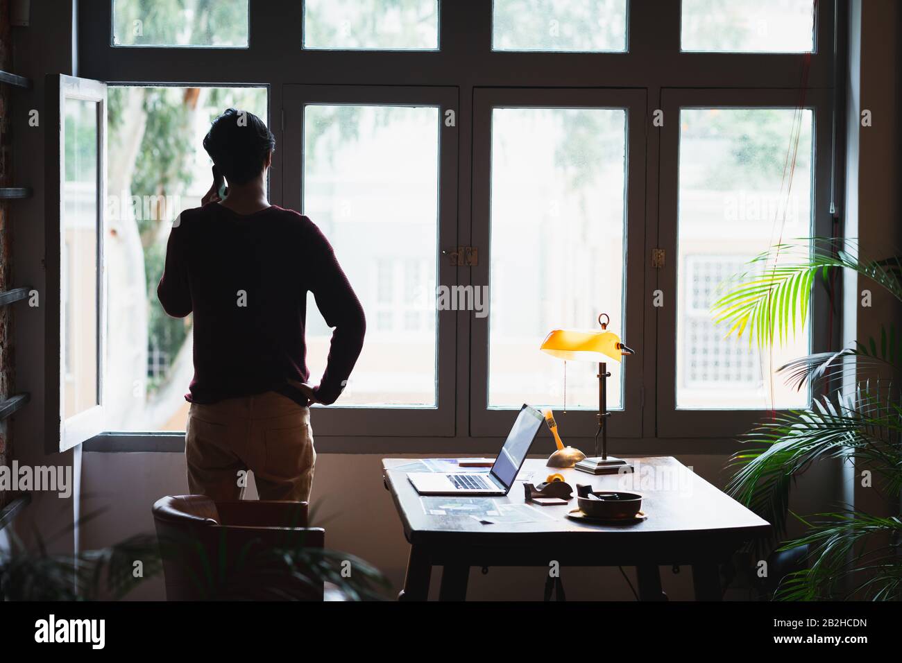 Young man looking through the window Stock Photo - Alamy