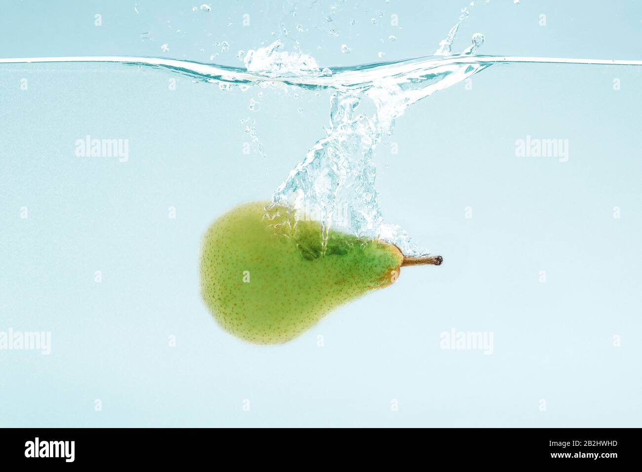 Juicy pear flying into water with splash on blue background Stock Photo ...