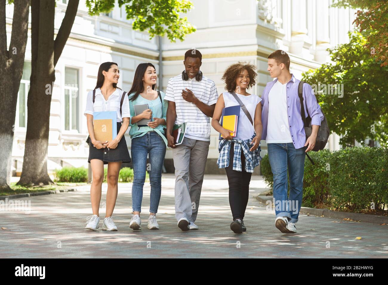 Group of multiethnic students walking together outdoors in college ...
