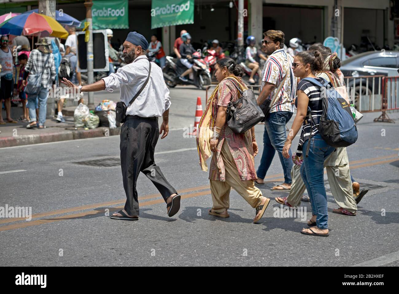 Crossing the road. Asian Indian family crossing the road and holding ...