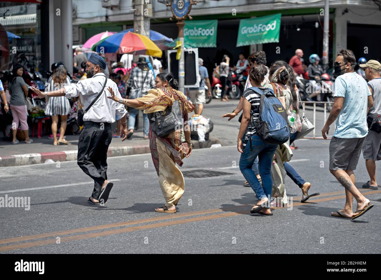 Crossing the road. Asian Indian family crossing the road and holding ...