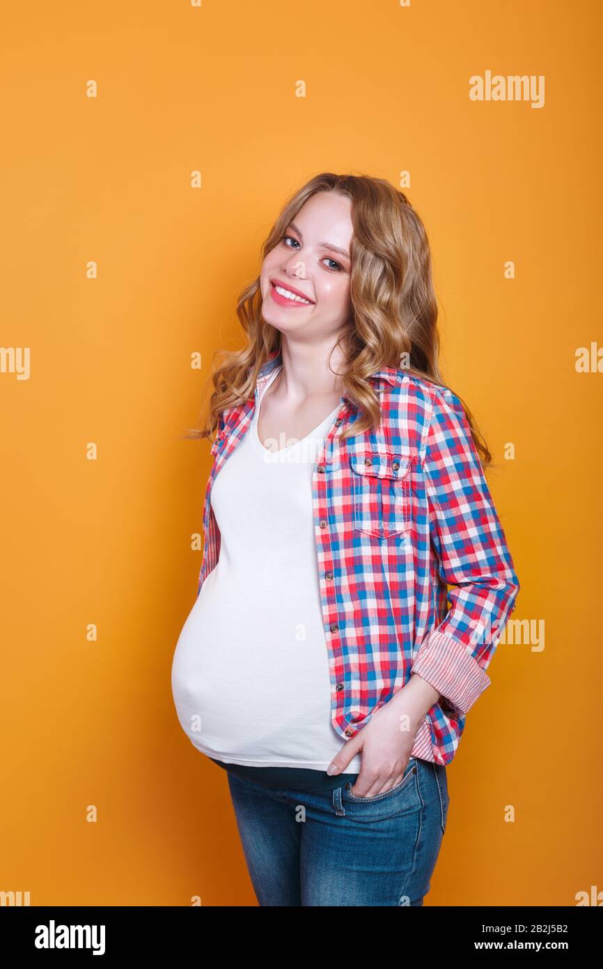 Happy pregnant woman with big belly on yellow background Stock Photo ...