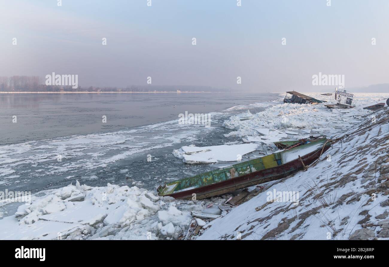 Small fishing boats trapped on frozen river Danube and many ice cubes ...