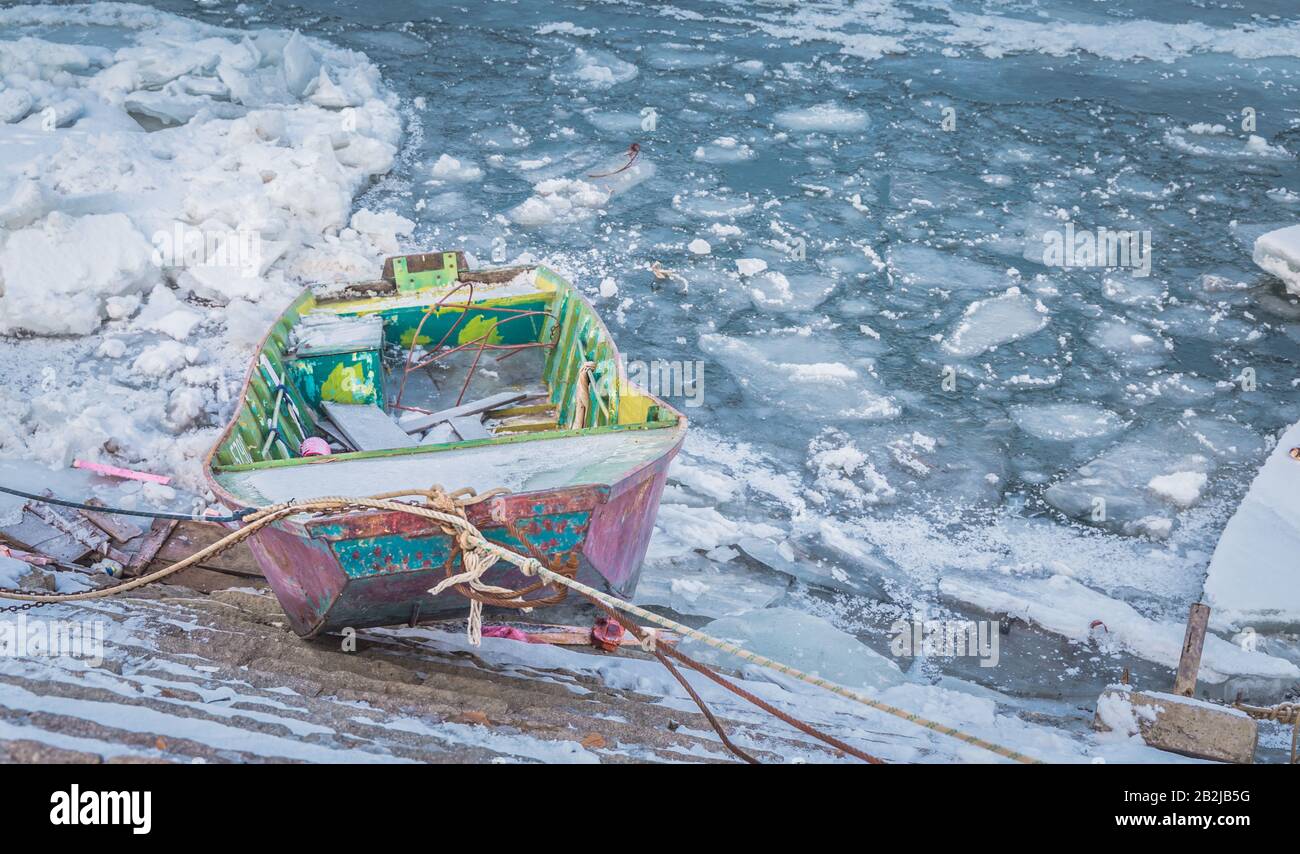 Small multicolor fishing boats trapped on frozen river Danube and many ...