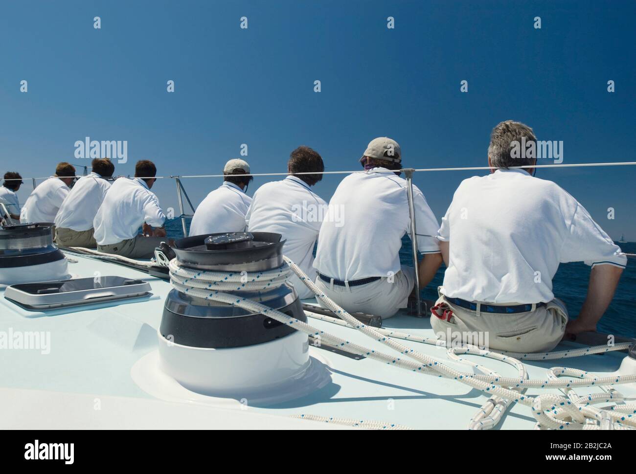 Sailing crew sitting on side of yacht on ocean back view Stock Photo ...