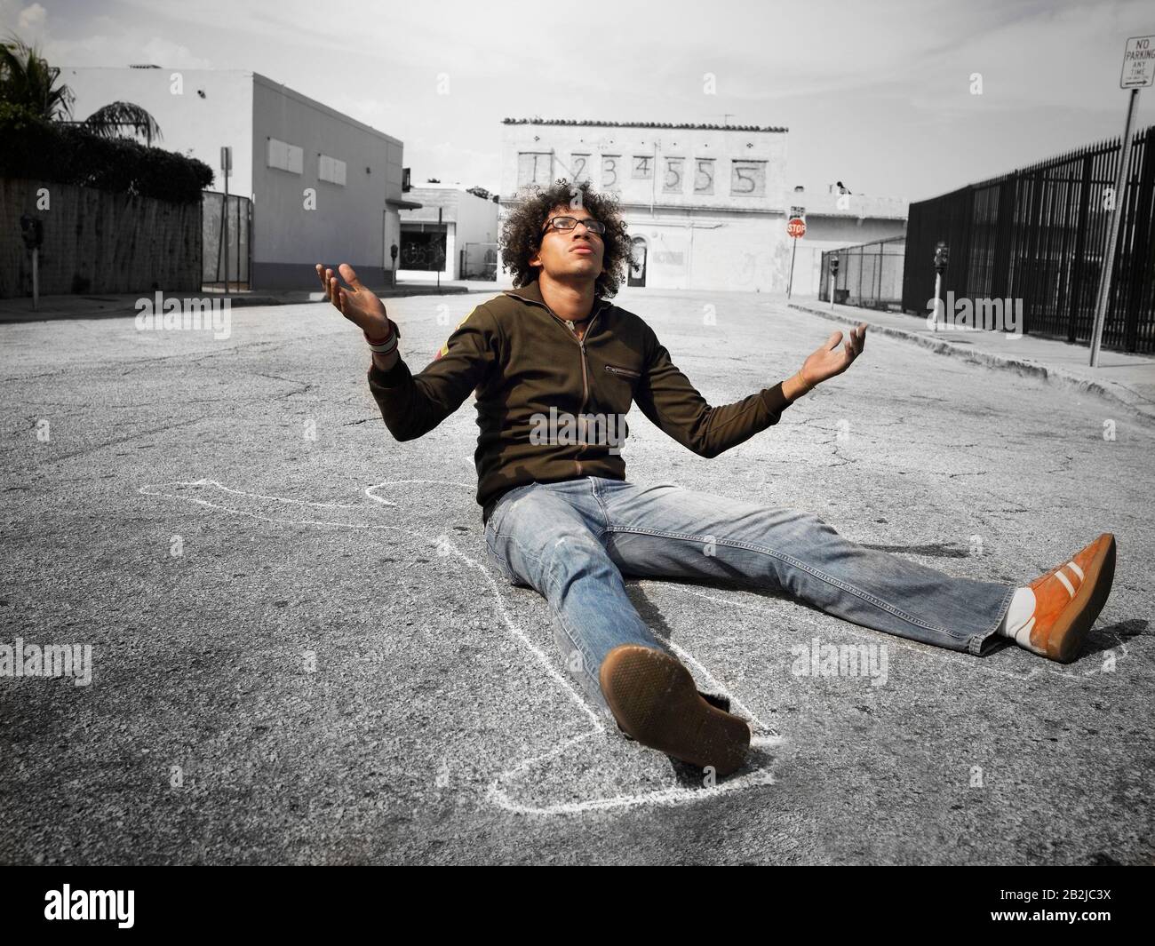 Confused young man sitting in street Stock Photo - Alamy