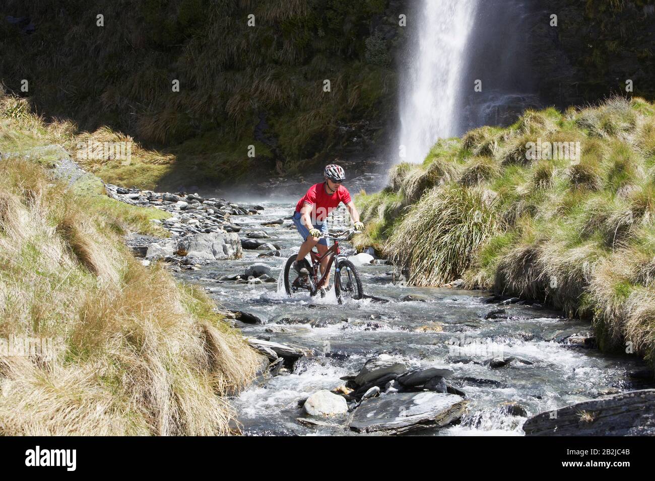 Cyclist riding in river with waterfall Stock Photo - Alamy
