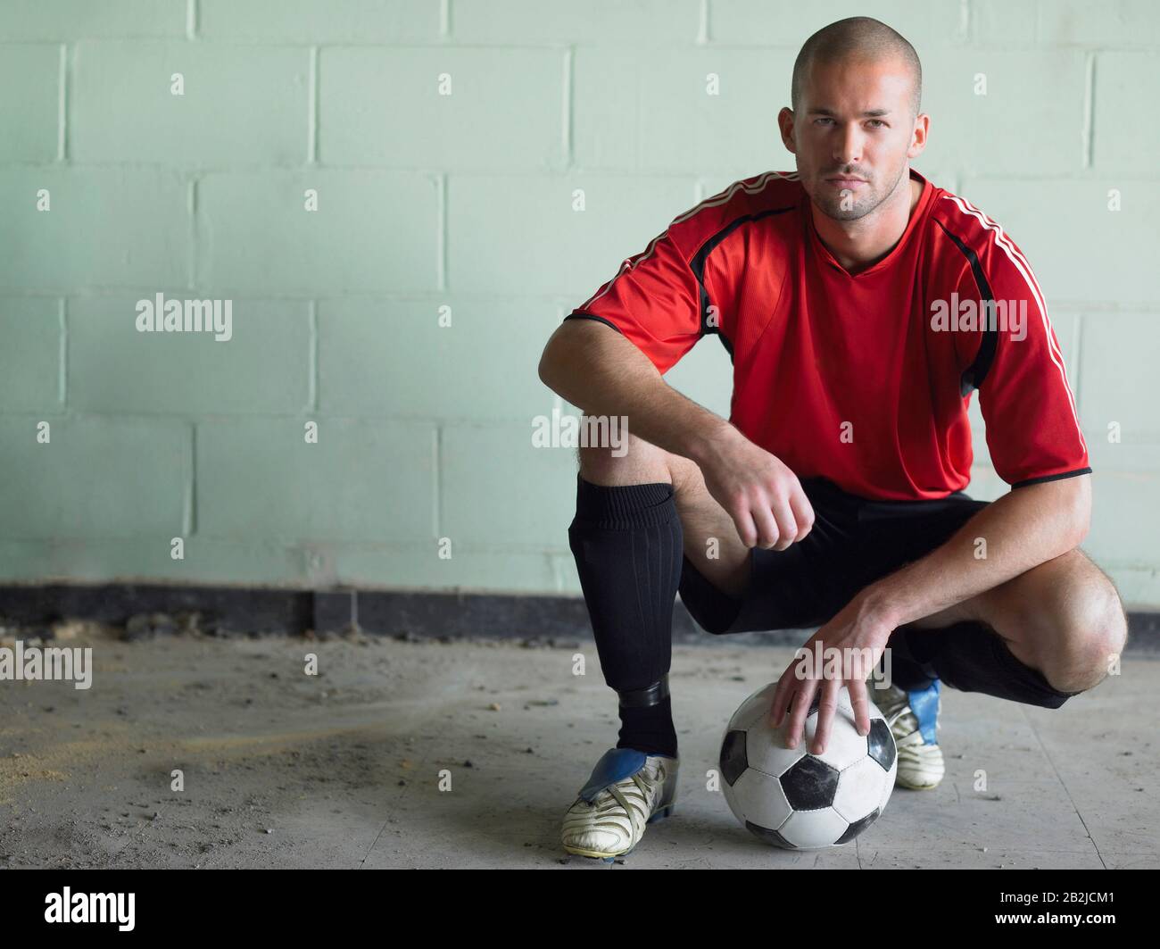 Soccer player crouching with ball portrait Stock Photo - Alamy