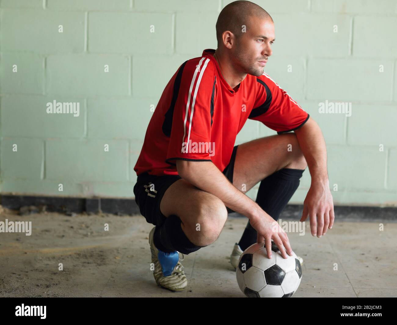 Soccer player crouching with ball side view Stock Photo - Alamy