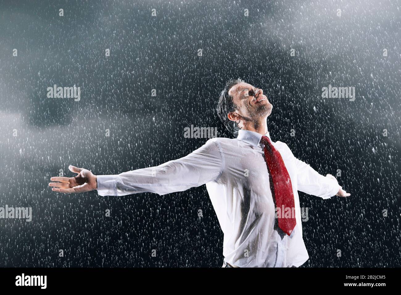 Businessman standing arms spread facing incoming rain Stock Photo - Alamy