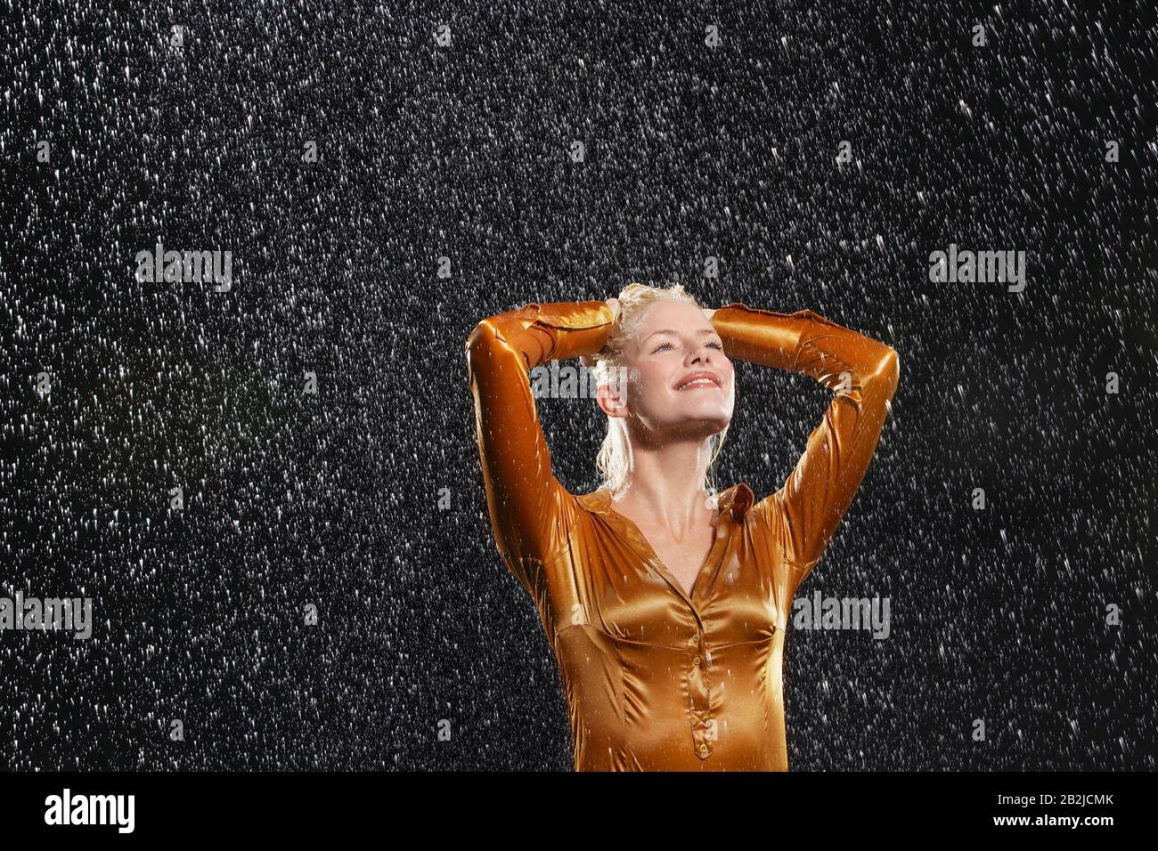Woman Standing in Rain arms raised letting raindrops fall on face Stock ...