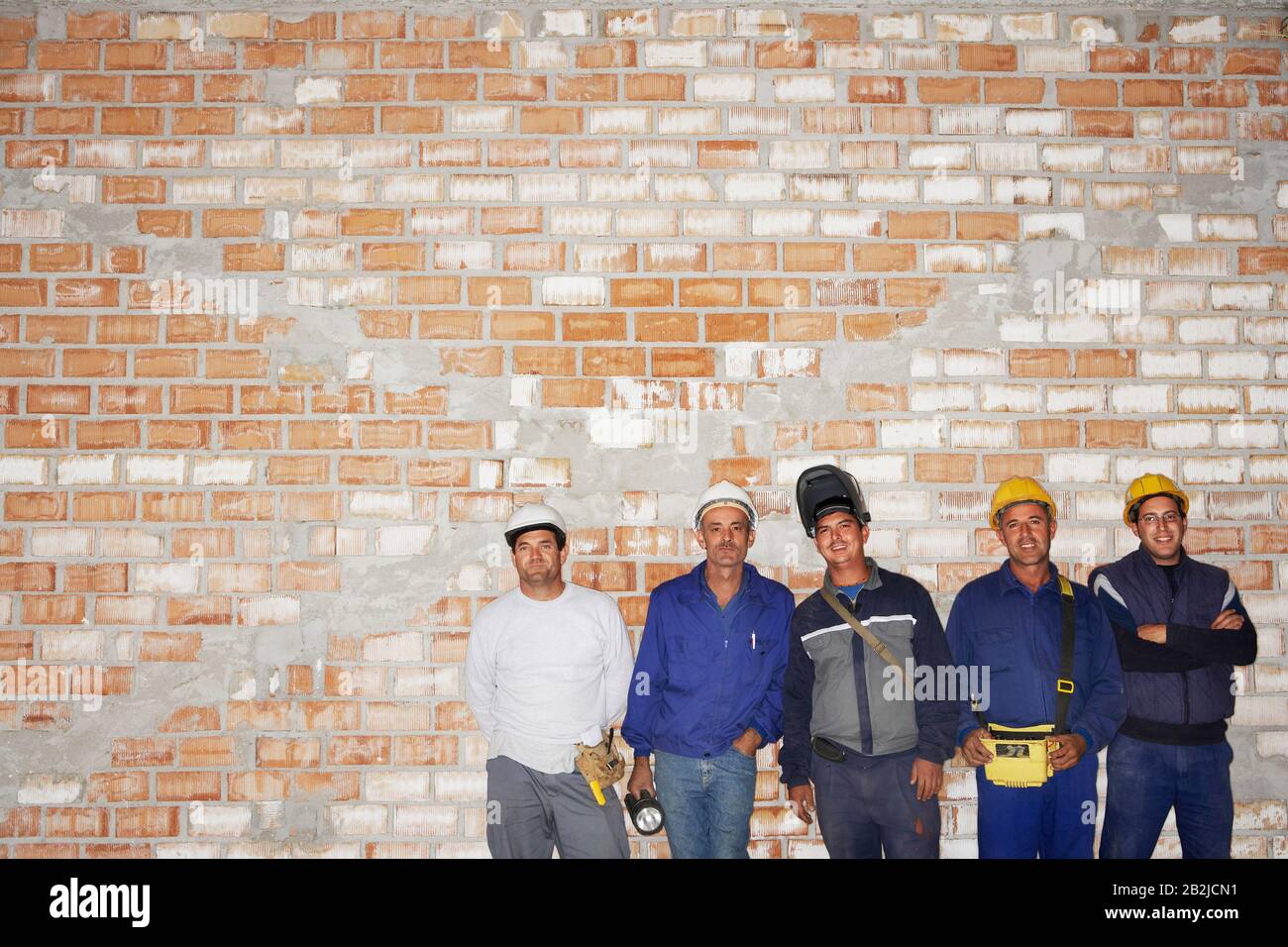 Group of construction workers standing by brick wall Stock Photo - Alamy