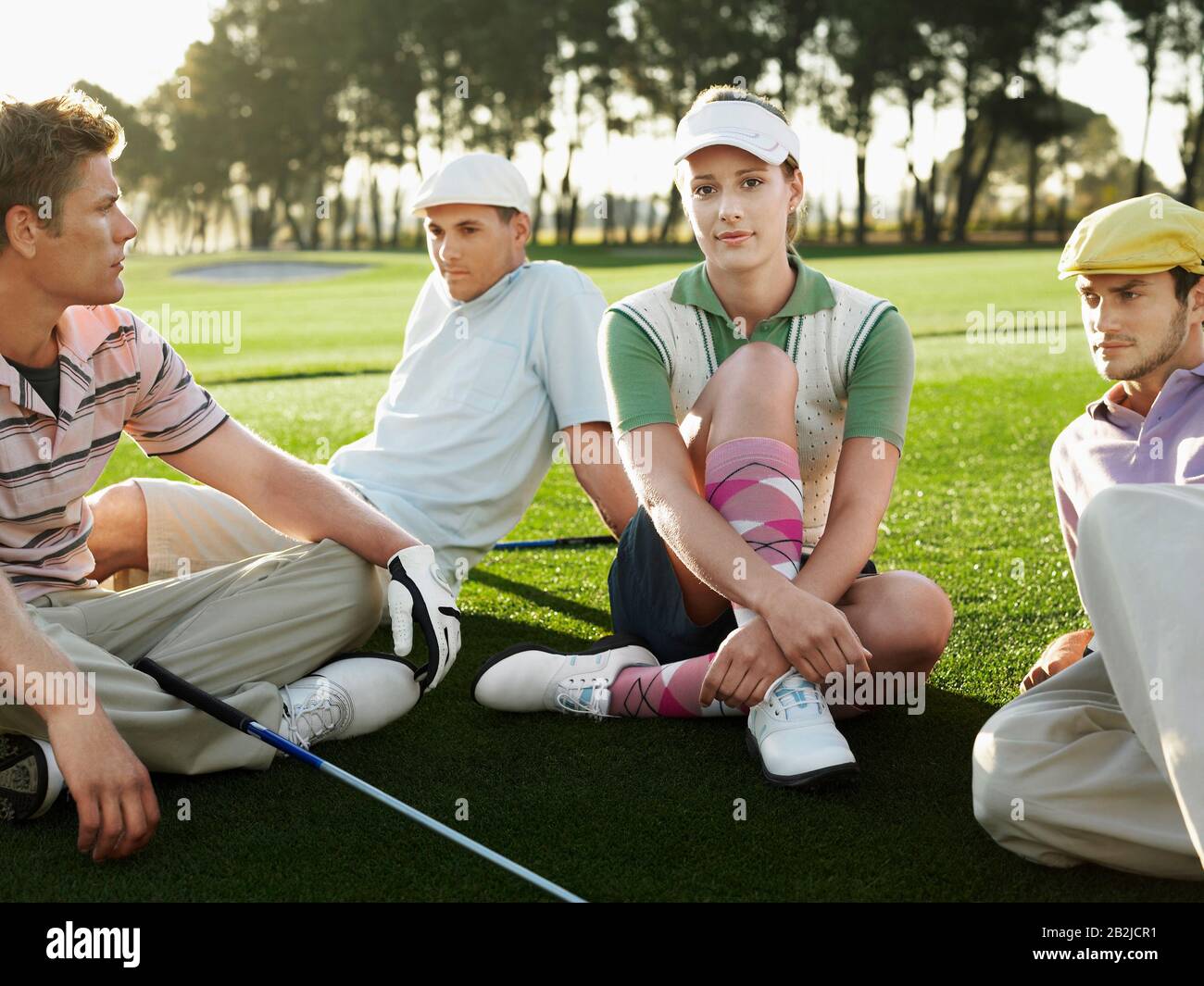 Four young golfers sitting on court Stock Photo - Alamy