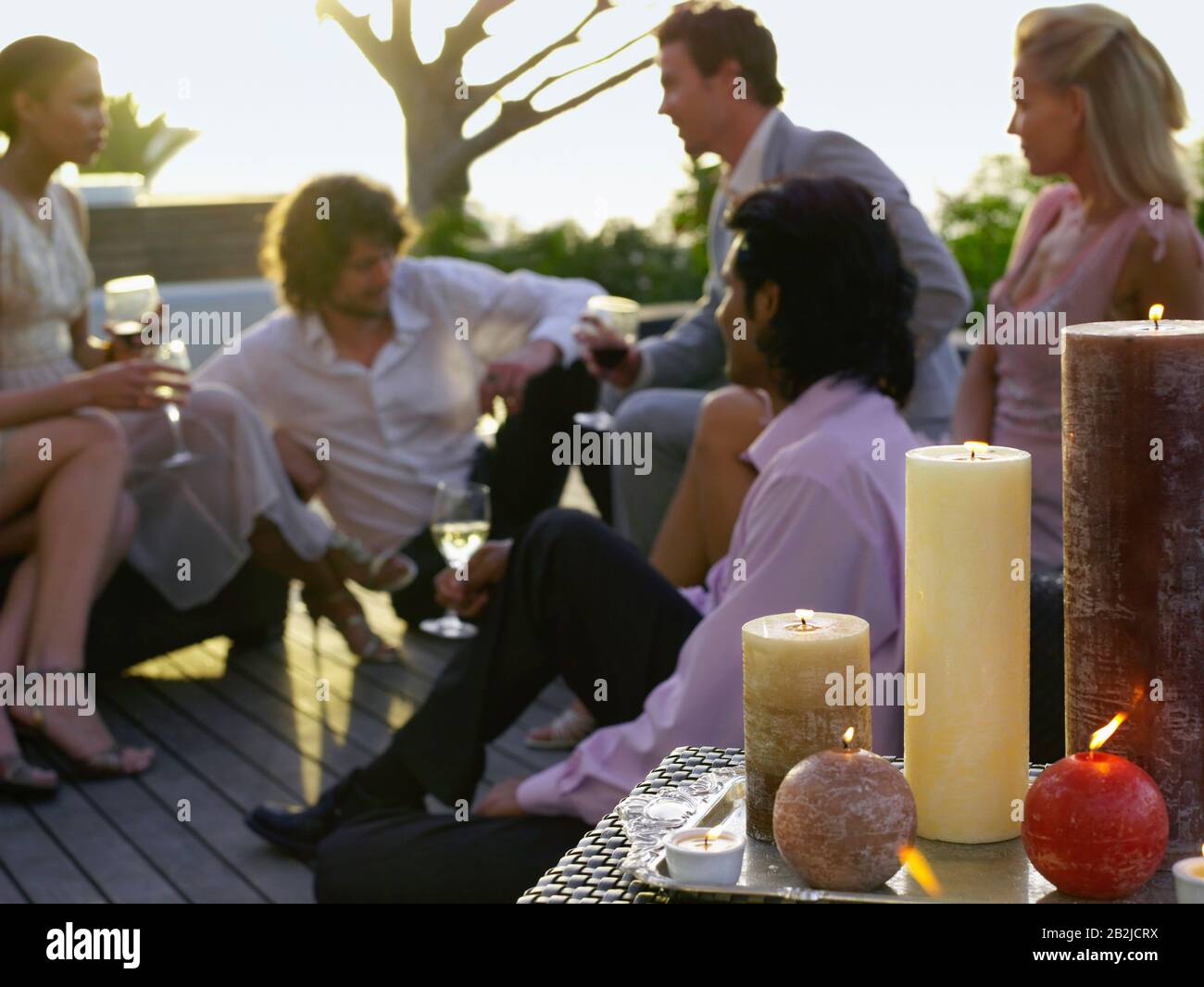 Friends sitting on porch Drinking and socialising near candle ...