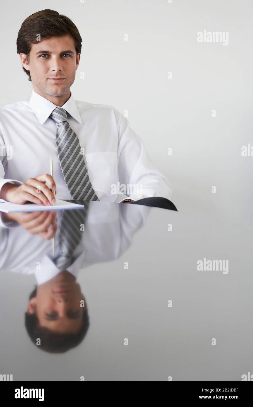 Business man sitting at conference table portrait Stock Photo - Alamy