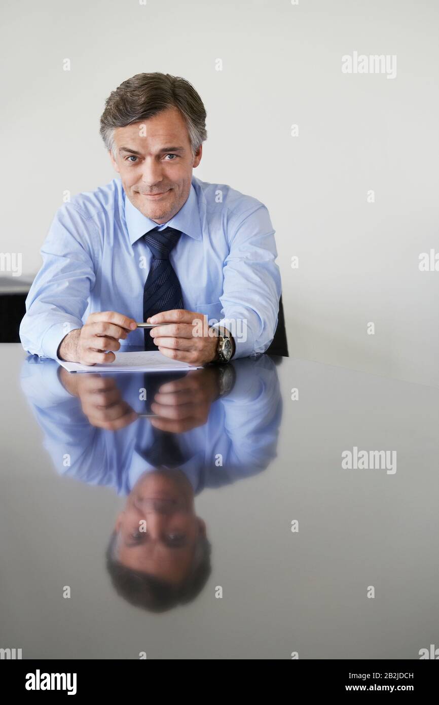 Business man sitting at conference table portrait Stock Photo - Alamy