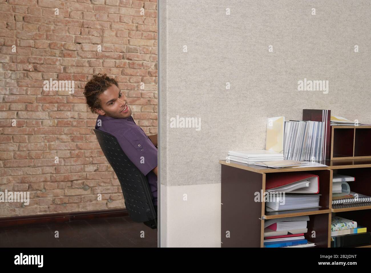 Man peering around corner in office Stock Photo - Alamy
