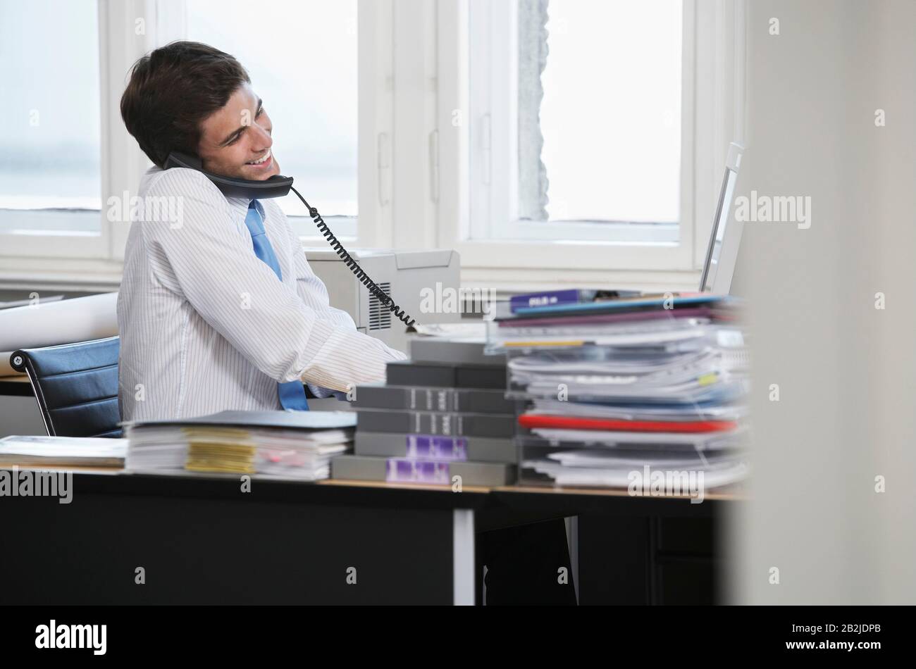 Business man using telephone at desk in office smiling Stock Photo - Alamy
