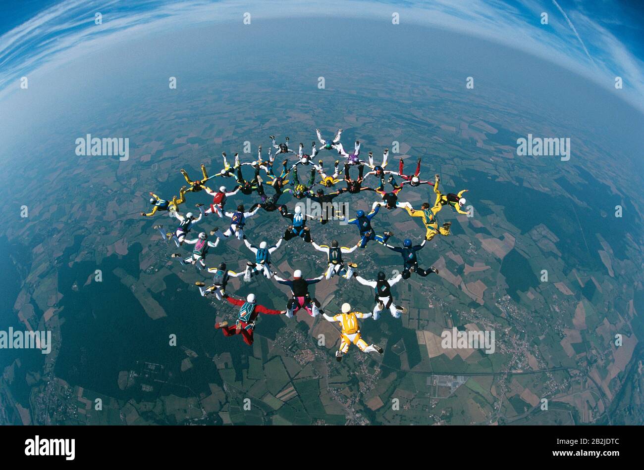 Large group of skydivers flying in formation over earth elevated view ...