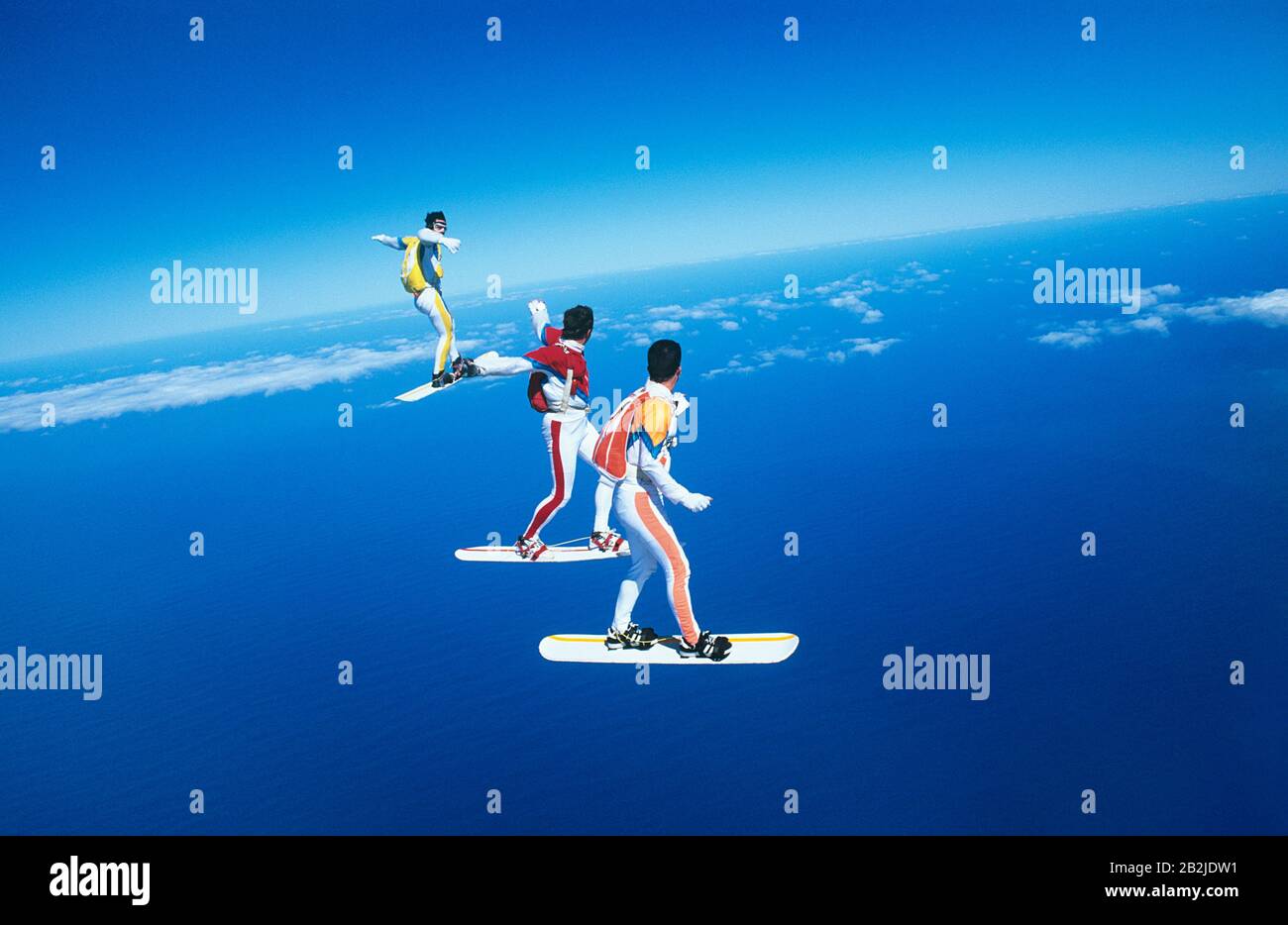 Three people skyboarding against blue sky Stock Photo - Alamy