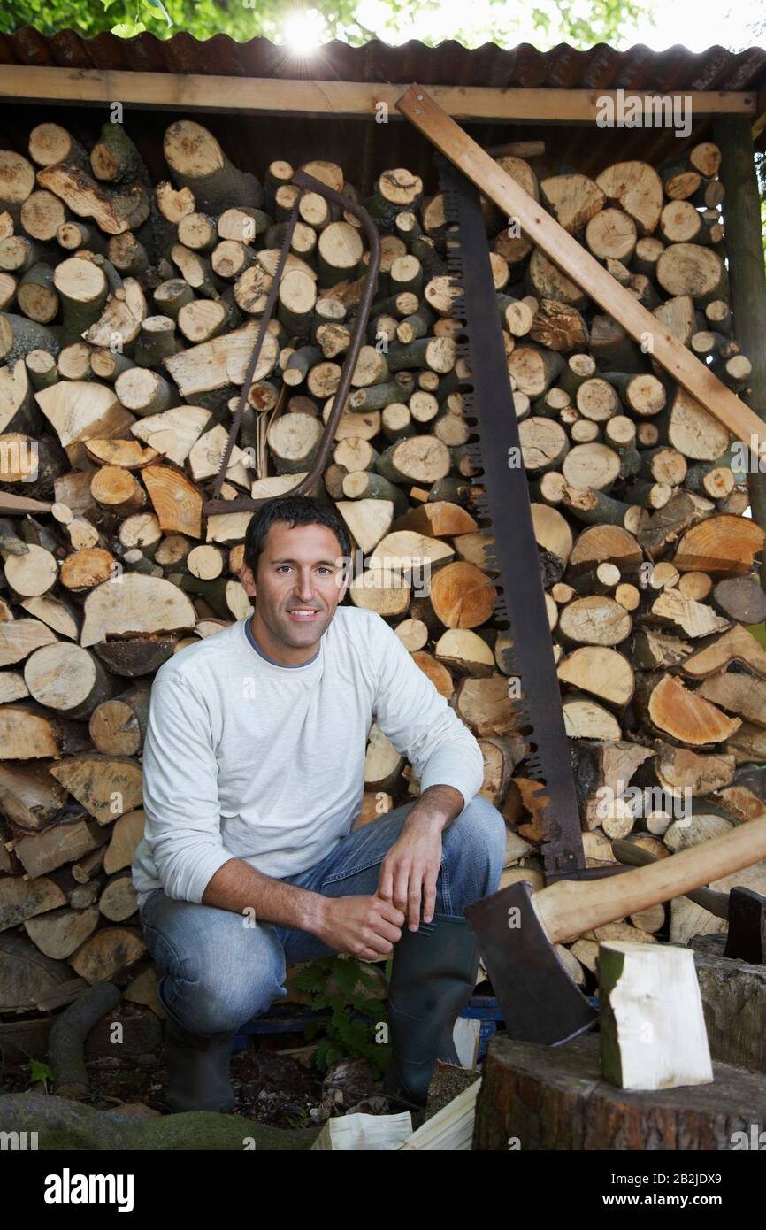 Man crouching beside axe at timber shed portrait Stock Photo - Alamy