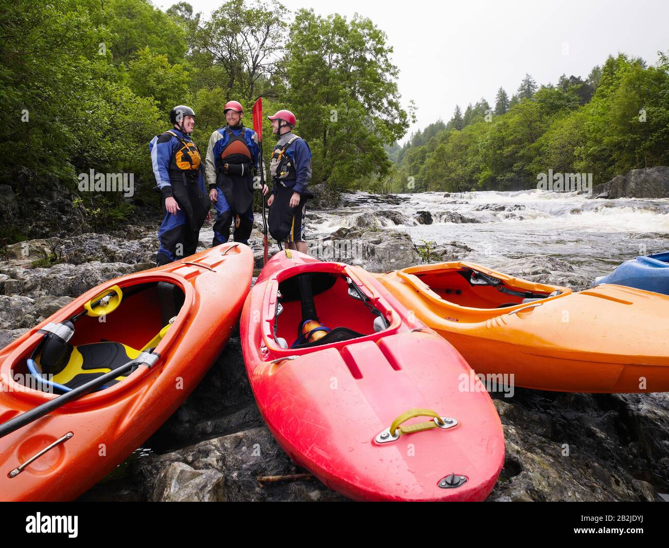 Three men with kayaks by river Stock Photo - Alamy