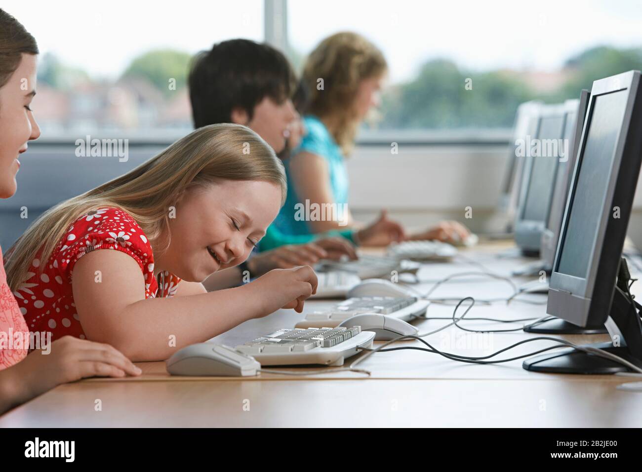 Girl (10-12) with Down syndrome using computer in computer lab children ...