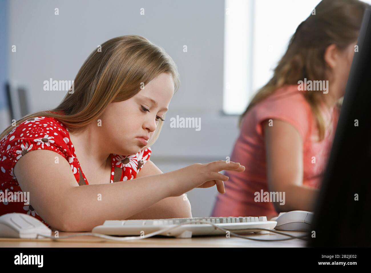 Girl (10-12) with Down syndrome using computer in computer lab children ...
