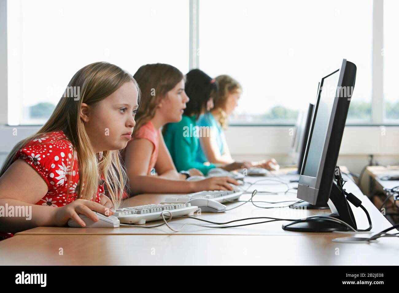 Girl (10-12) with Down syndrome using computer in computer lab children ...
