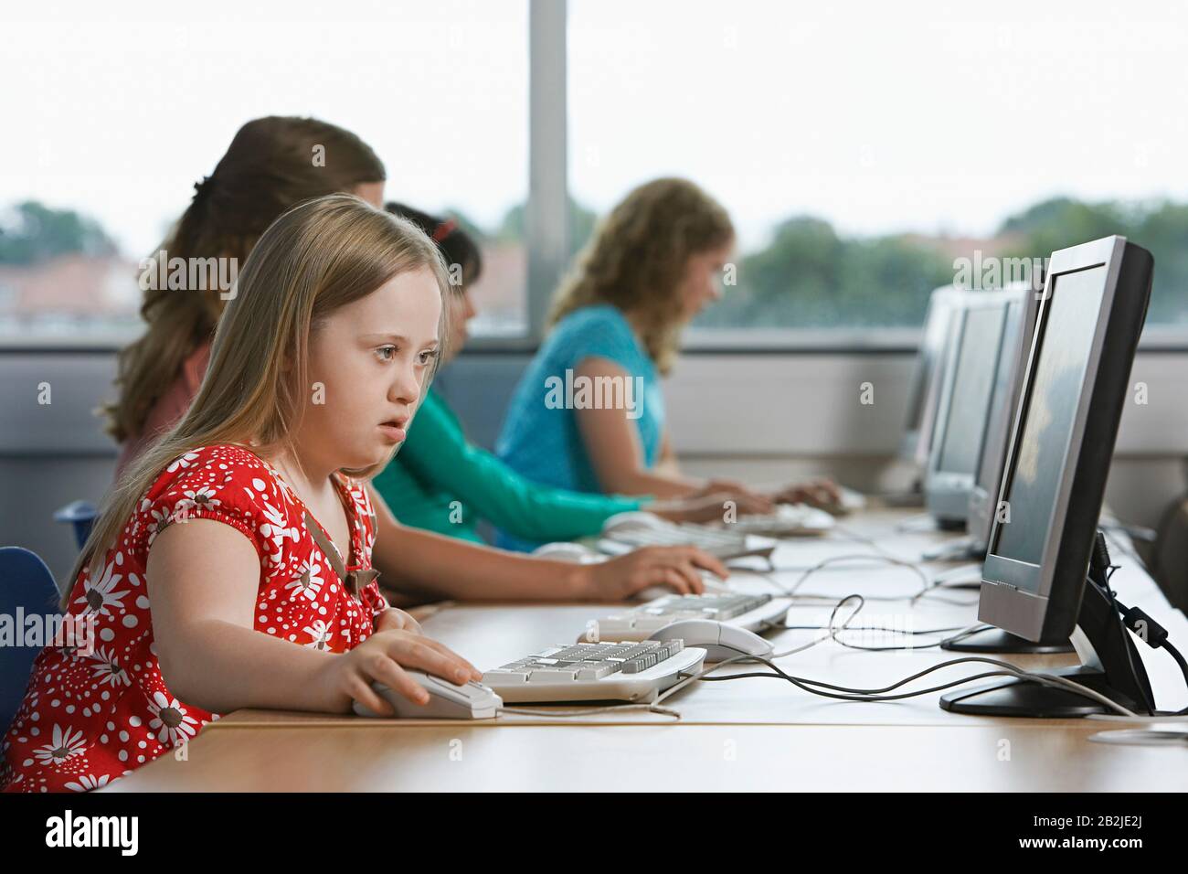 Girl (10-12) with Down syndrome using computer in computer lab children ...