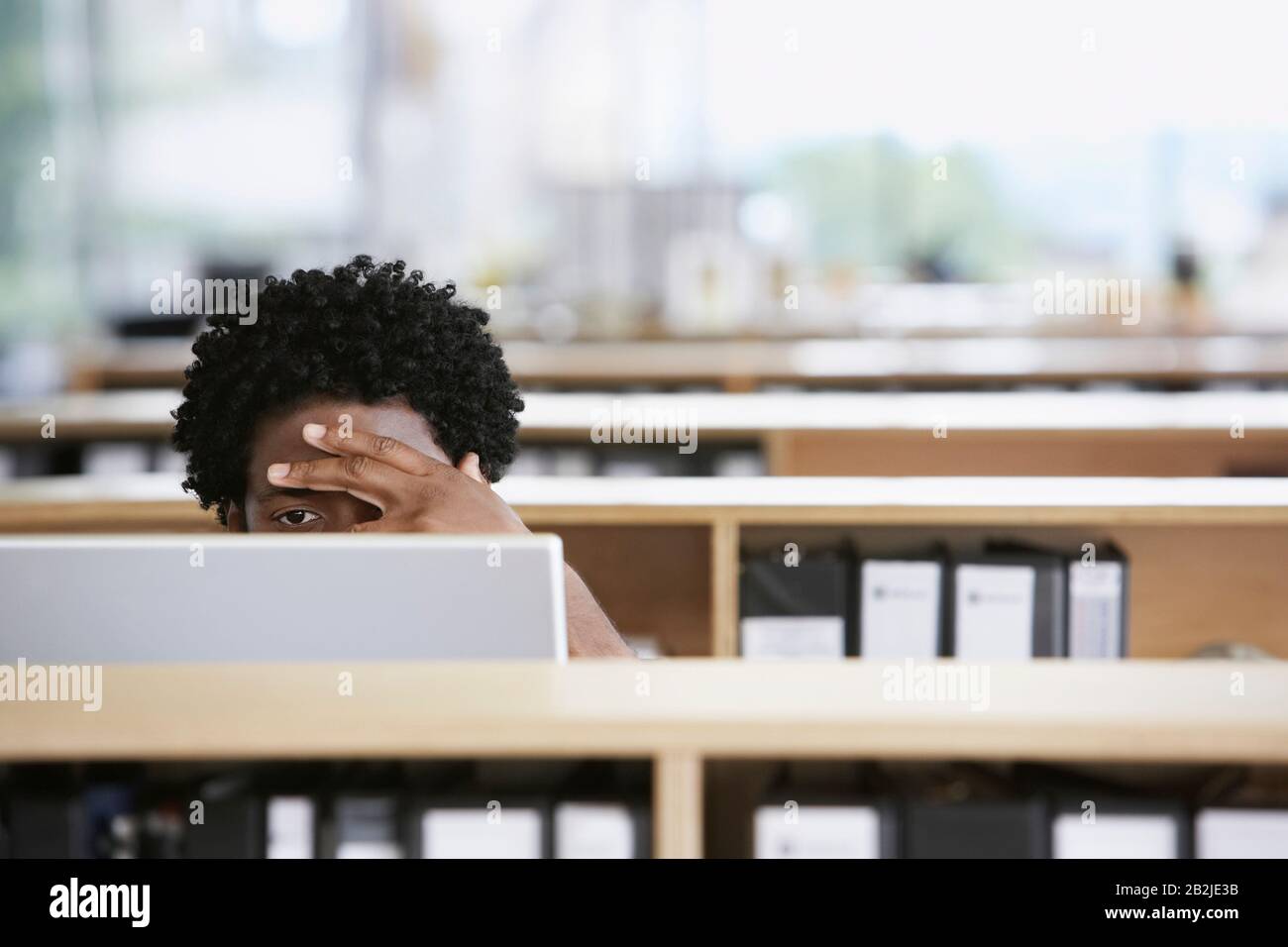 Man hiding behind office desk Stock Photo - Alamy