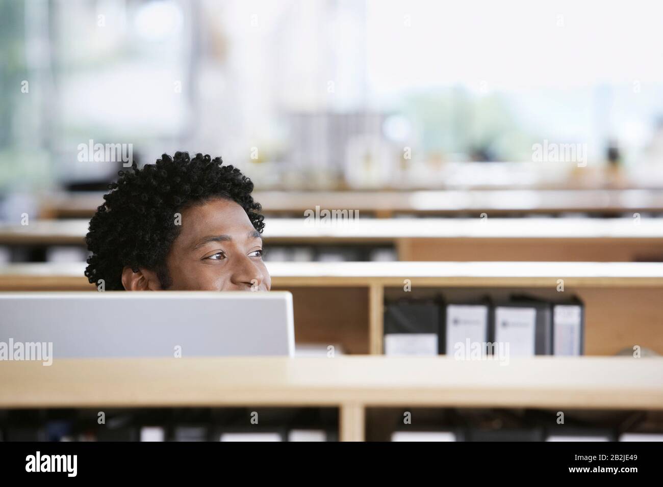 Man hiding behind office desk Stock Photo - Alamy