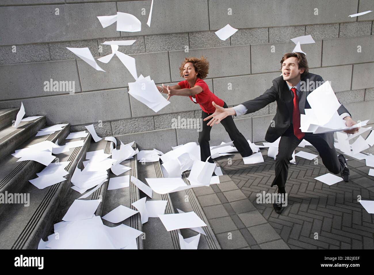 Busines man and woman catching falling paperwork on steps Stock Photo ...