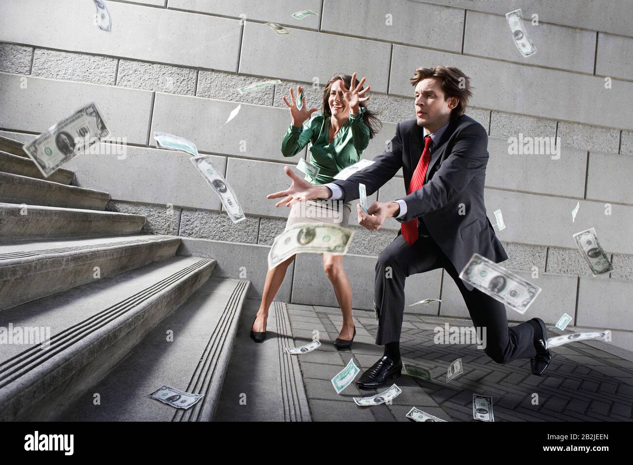 Busines man and woman catching falling money on steps Stock Photo - Alamy